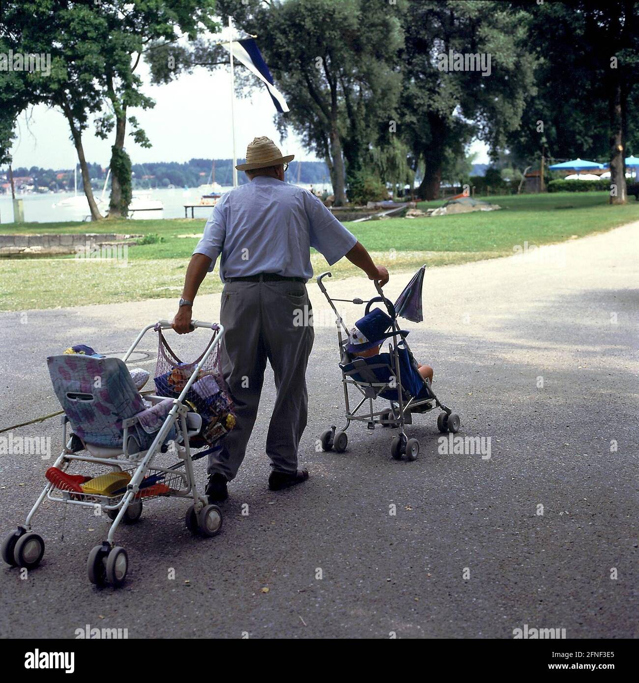 A grandfather pulls the strollers of his two grandchildren. [automated ...
