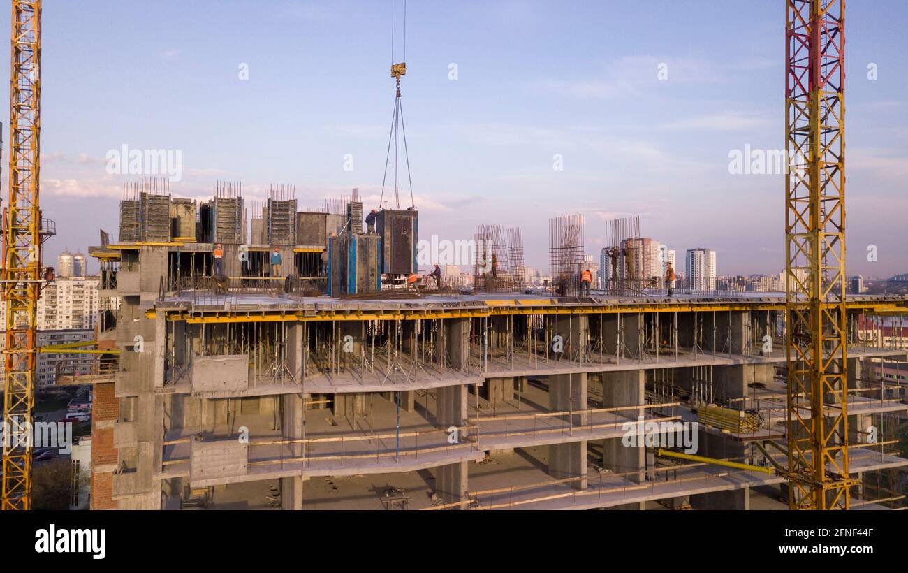 Workers on a high-rise building in the evening clog the formwork for ...