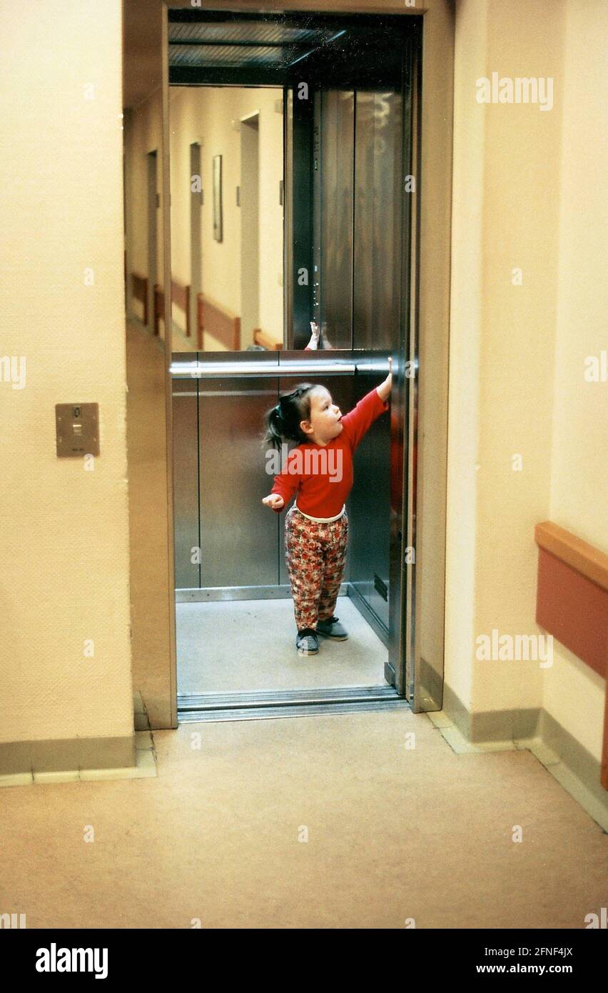 A small child stands in the elevator and pushes elevator buttons ...