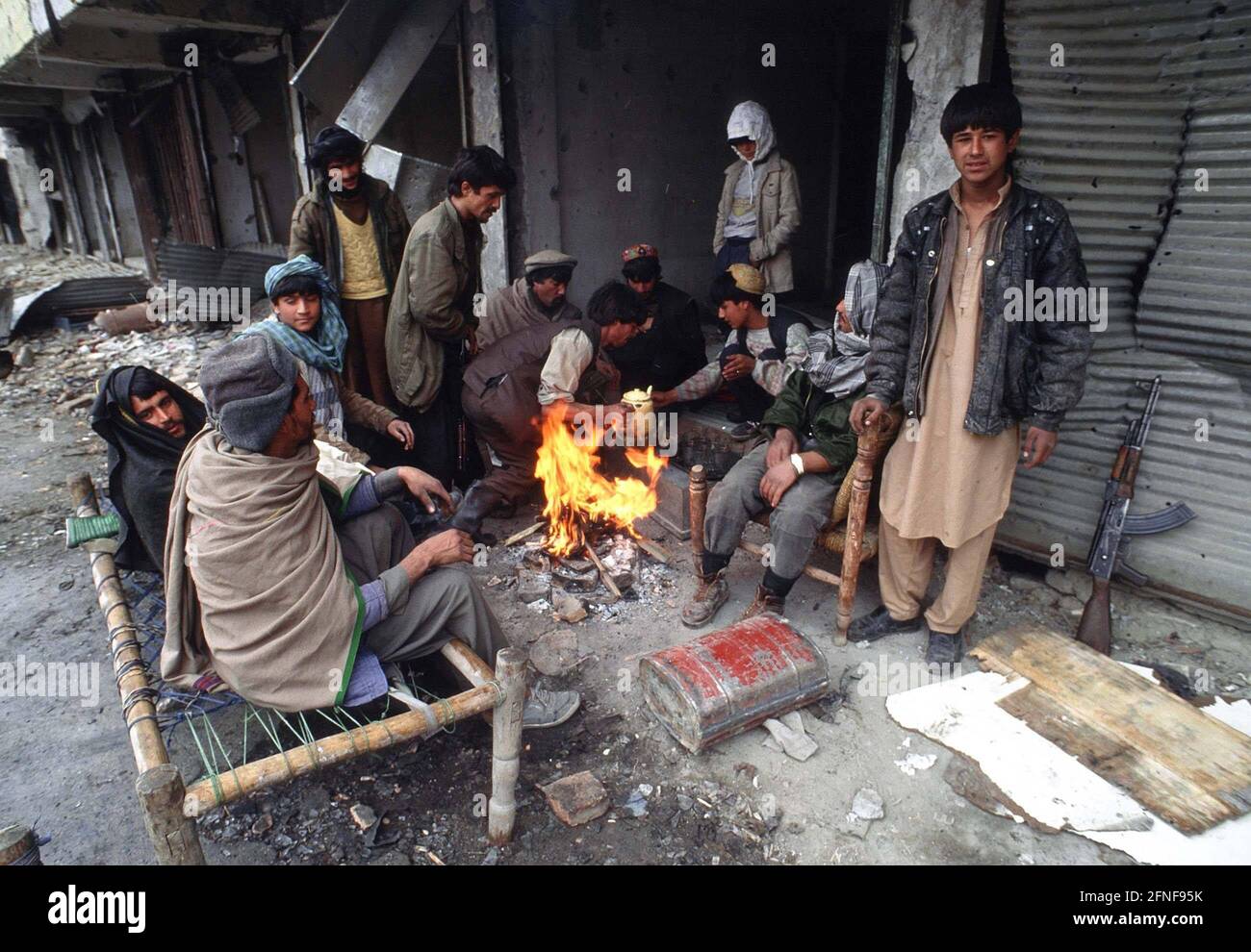 Men cluster around a fireplace, guarding their homes in the ruins of ...