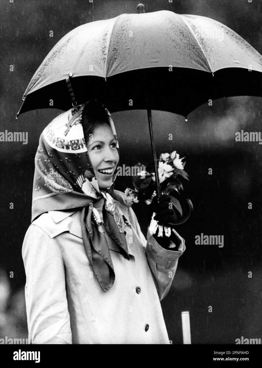 Princess Anne holds a bouquet of flowers in her hand and an umbrella ...