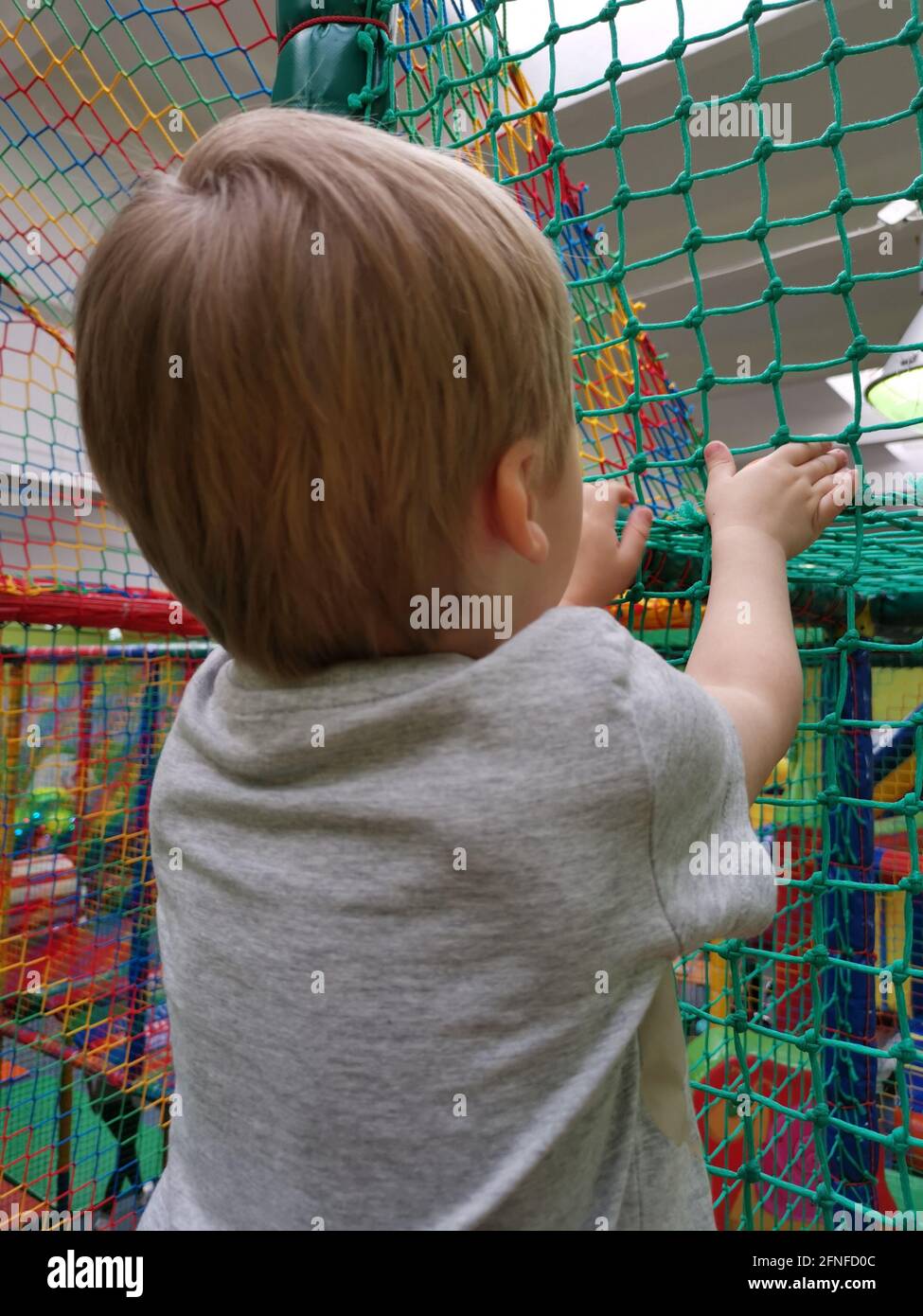Cute little boy holding a rope mesh while playing in the bright ...