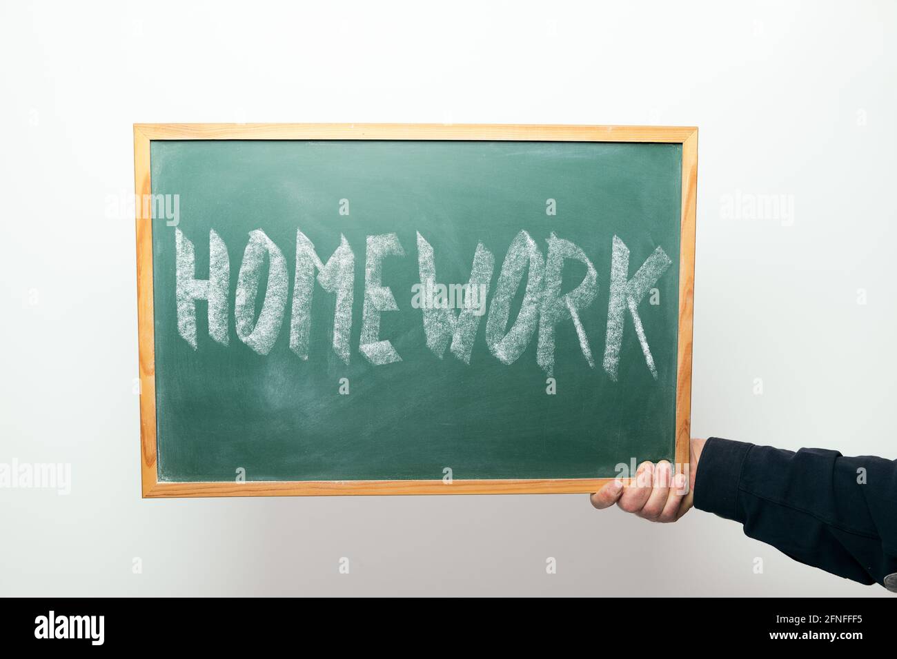 hand holding a chalkboard with the word HOMEWORK handwritten in chalk ...