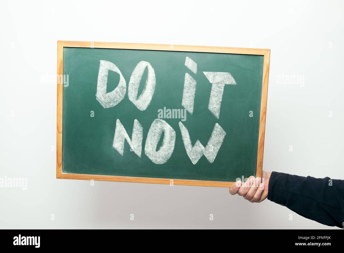 hand holding a chalkboard with the word DO IT NOW handwritten in chalk ...
