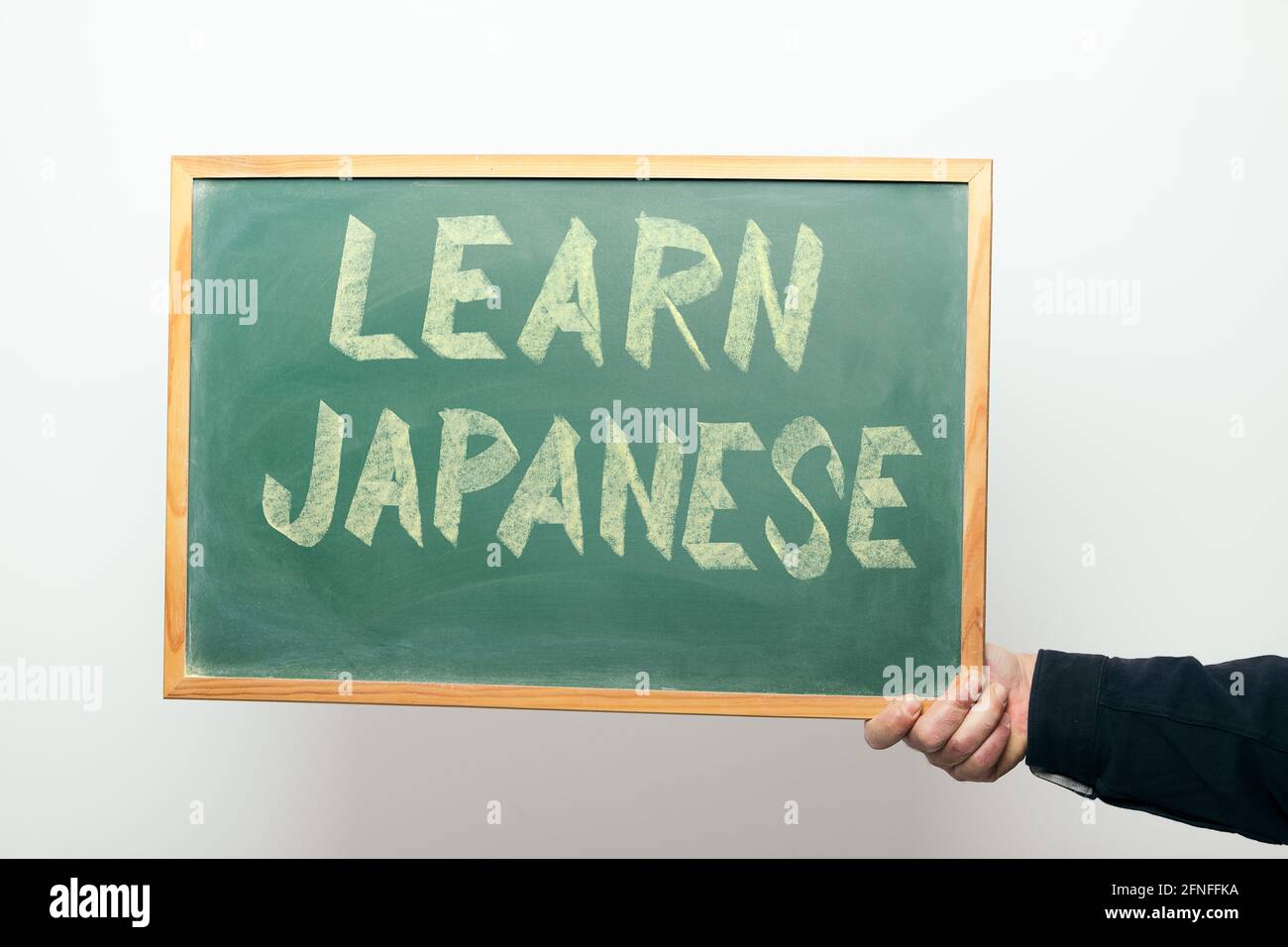 hand holding a chalkboard with the message LEARN JAPANESE handwritten ...
