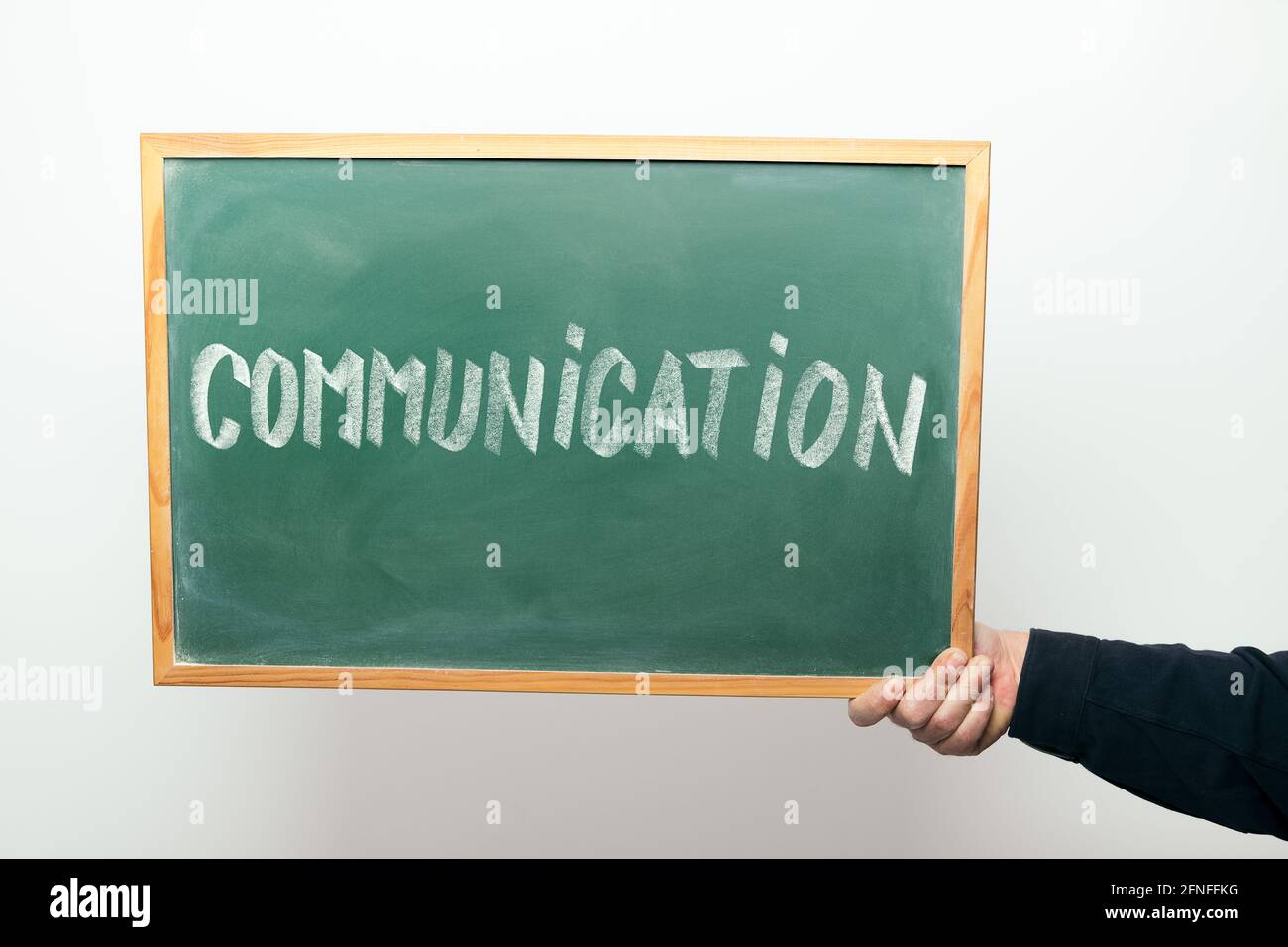 hand holding a chalkboard with the word COMMUNICATION handwritten in ...