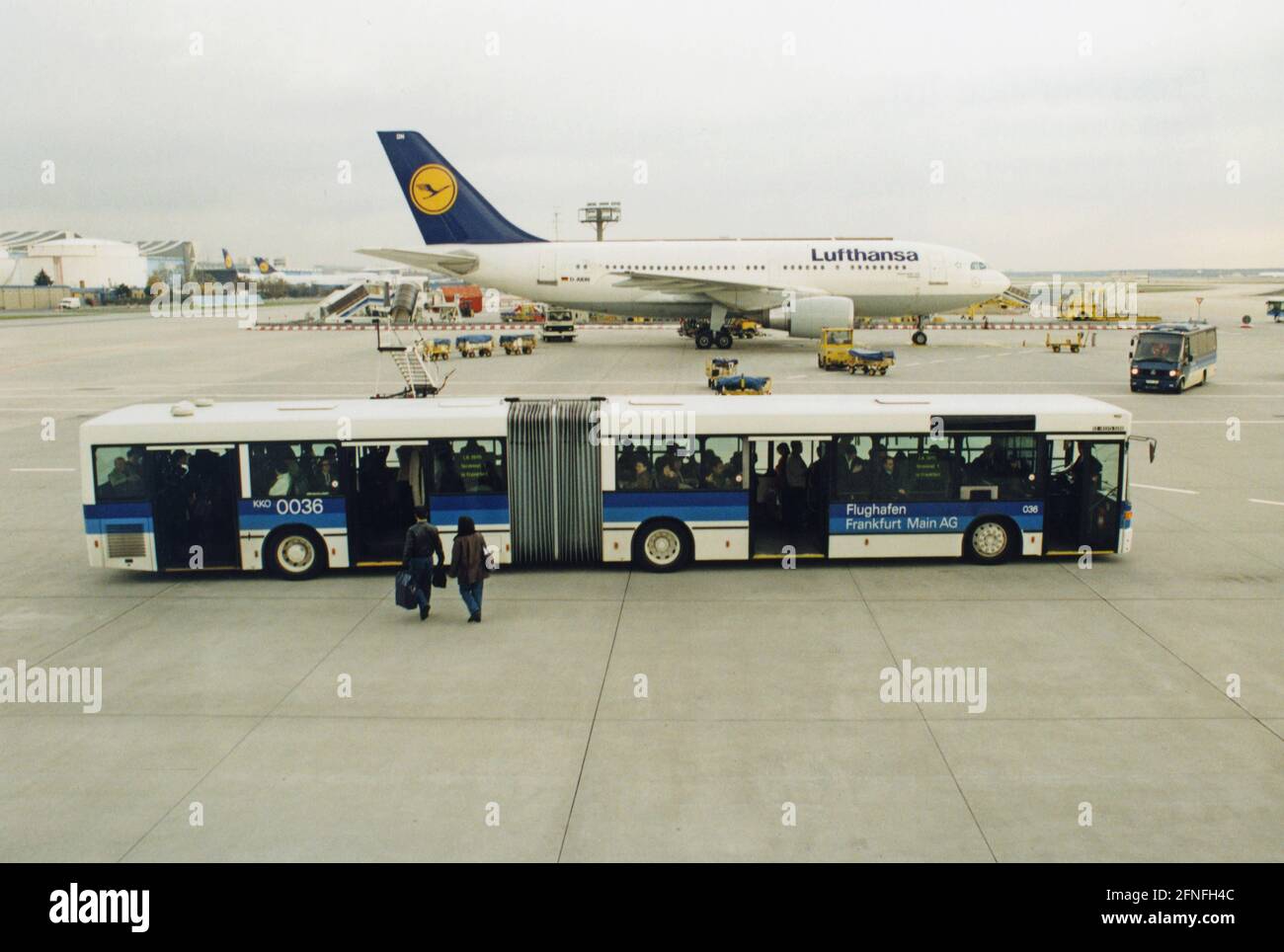 Passengers board a bus on the apron of Frankfurt Airport. In the ...
