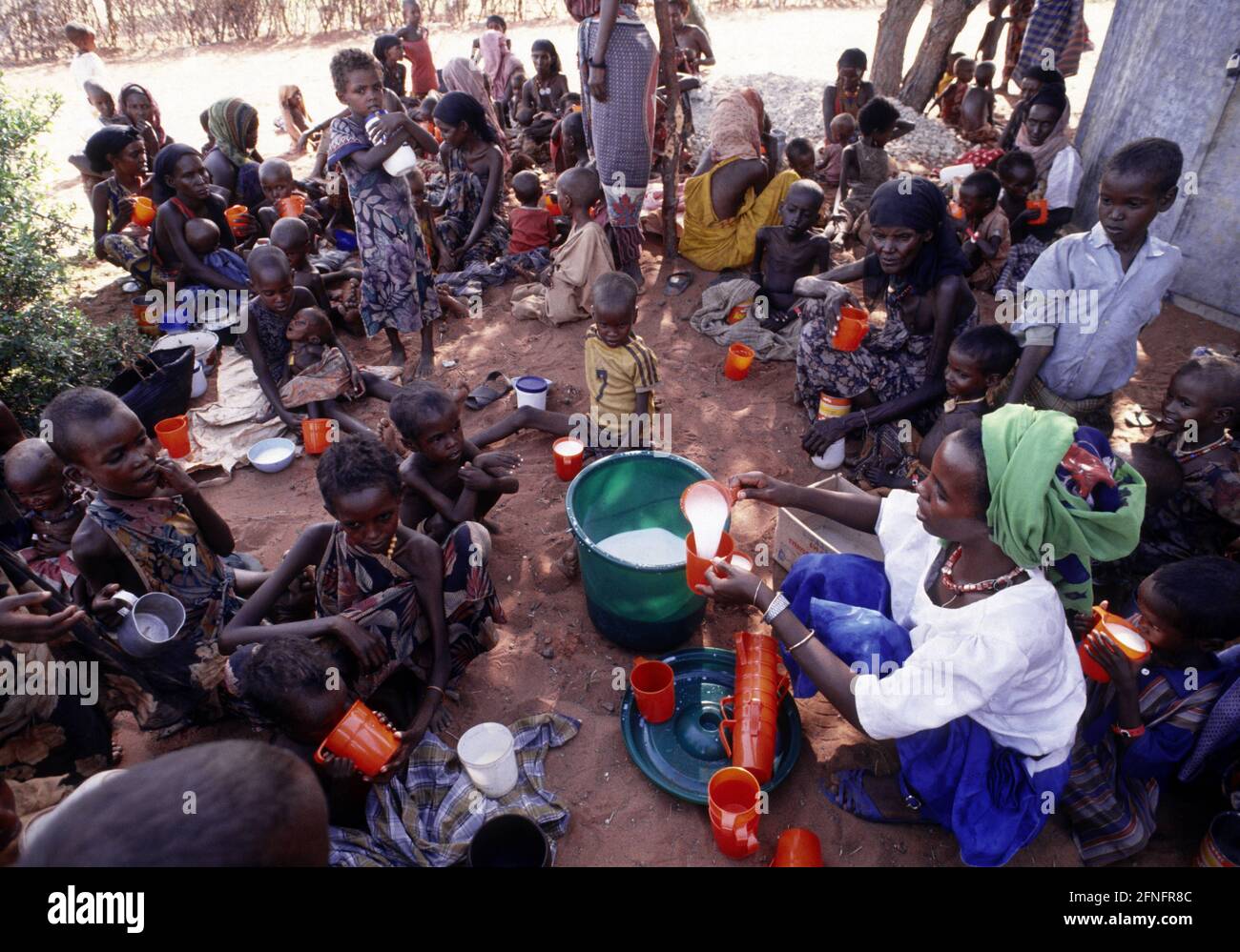 KEN , KENYA : A local aid worker distributes milk at a feeding centre ...