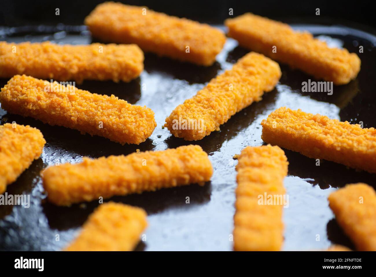 Fish sticks background. Fried fish sticks on a culinary baking sheet as ...