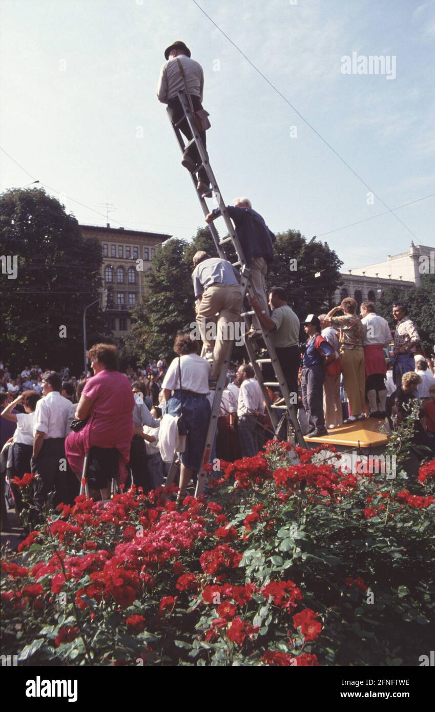 Spectators stand on a ladder to watch the traditional costume parade in ...