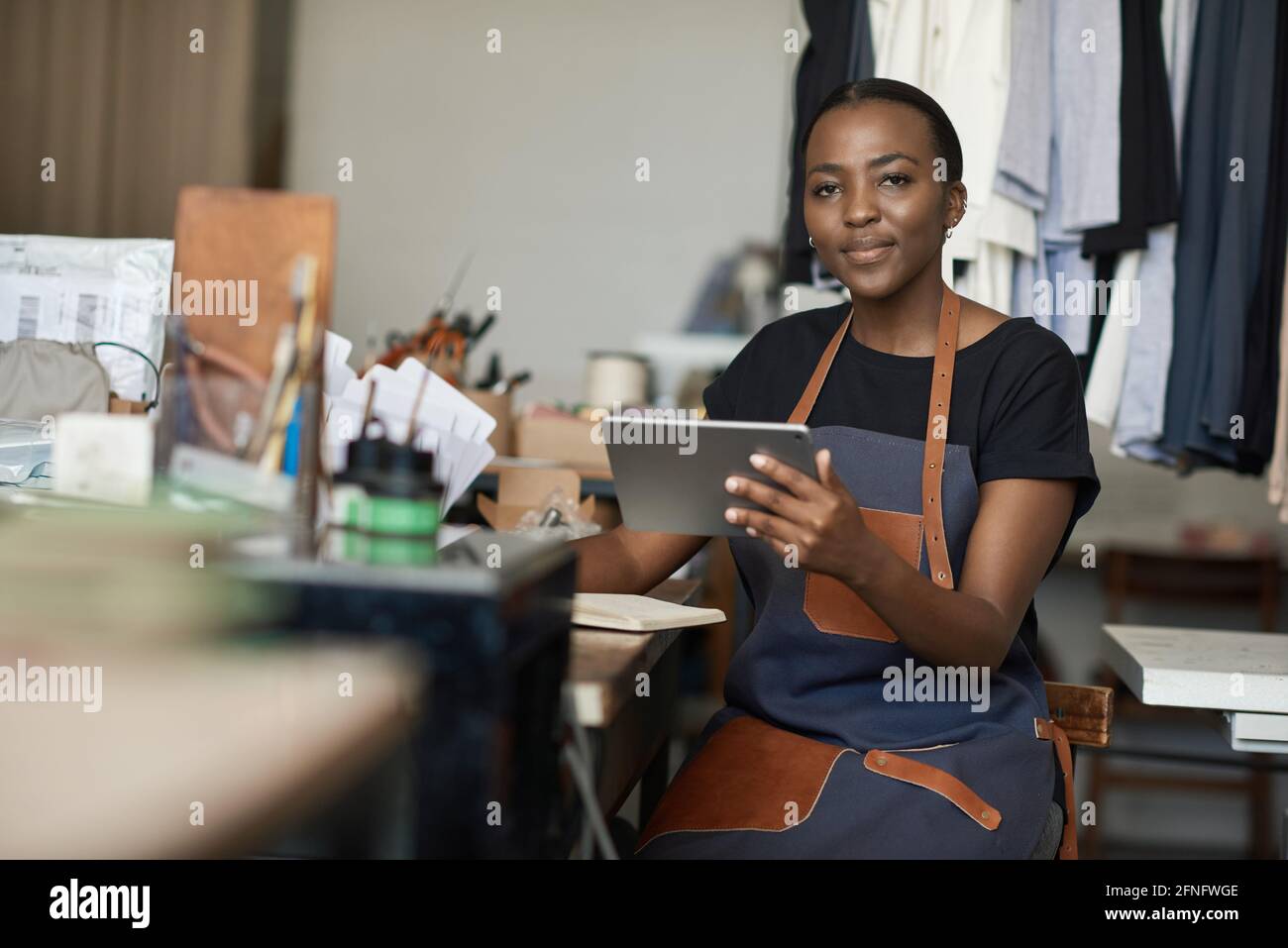 African female leather worker using a tablet in her studio Stock Photo ...