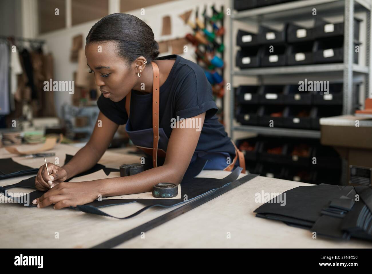 African female artisan using a pattern on leather in her shop Stock ...