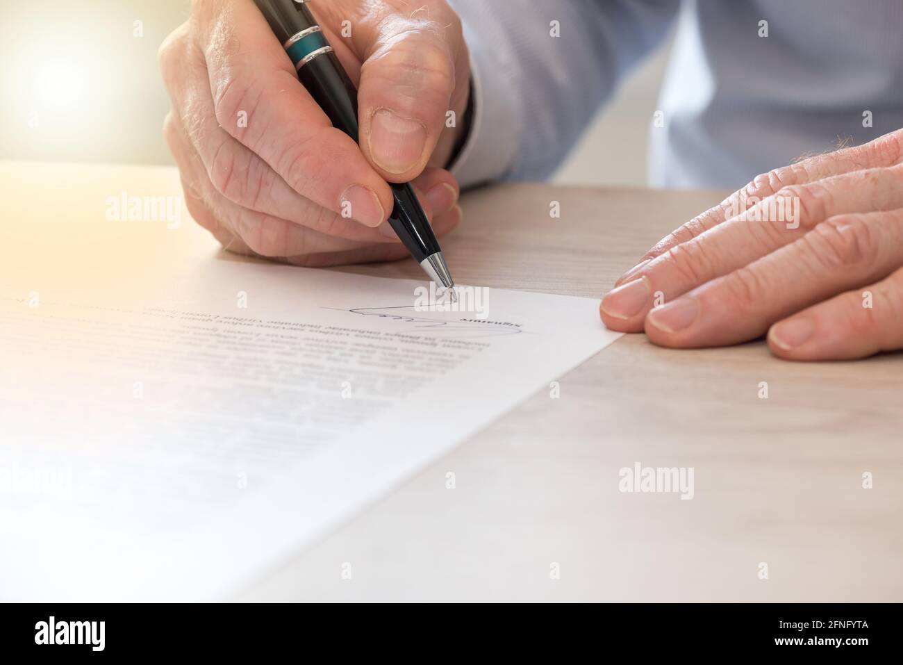 Man signing a legal document, light effect Stock Photo - Alamy