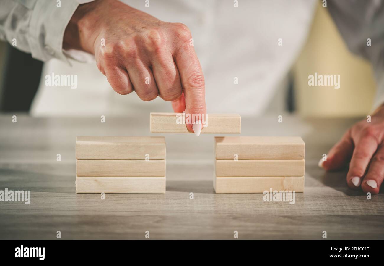 Female hand building a bridge with wooden blocks; concept of ...