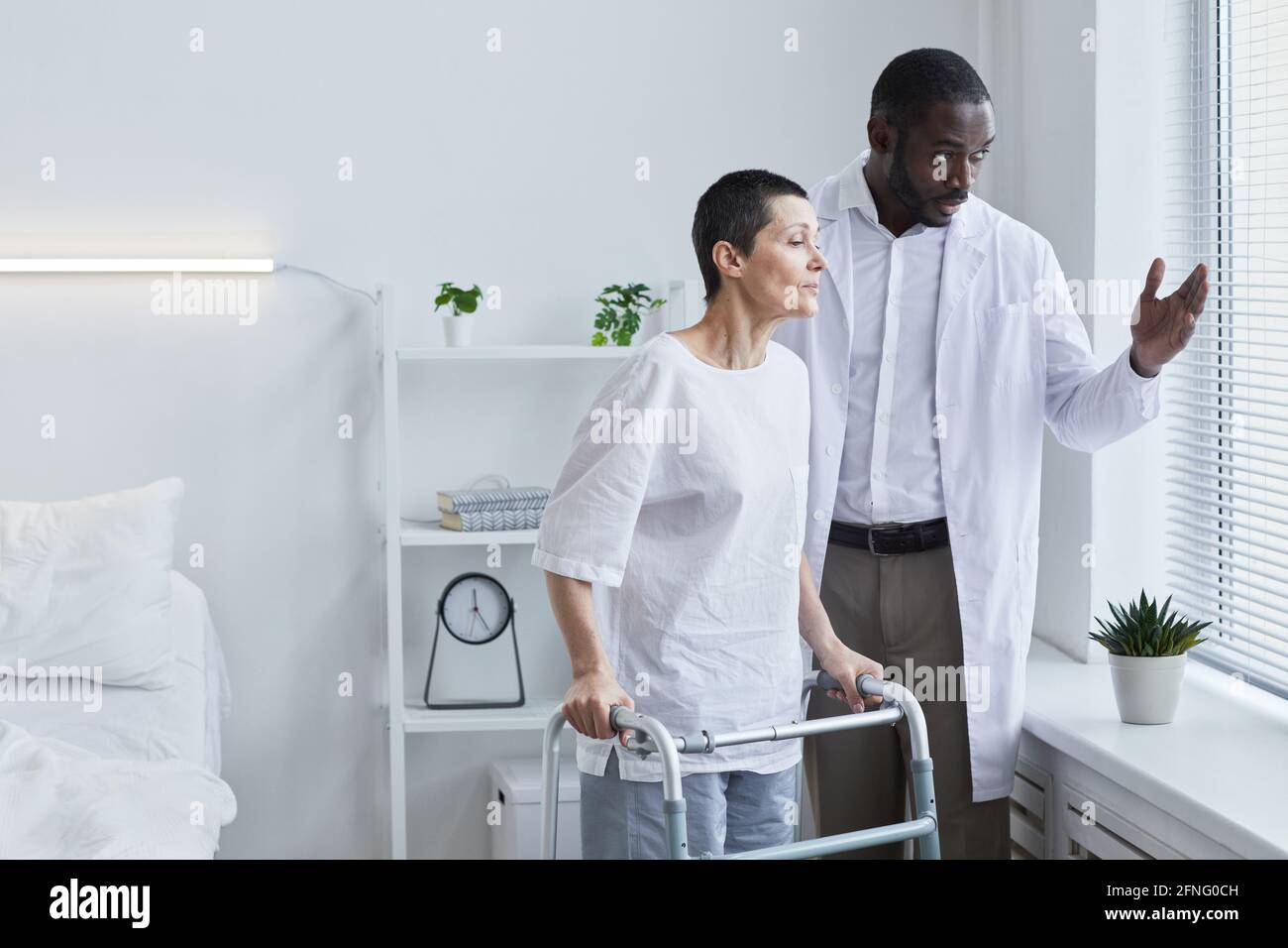 African young doctor supporting his patient while they standing at ...