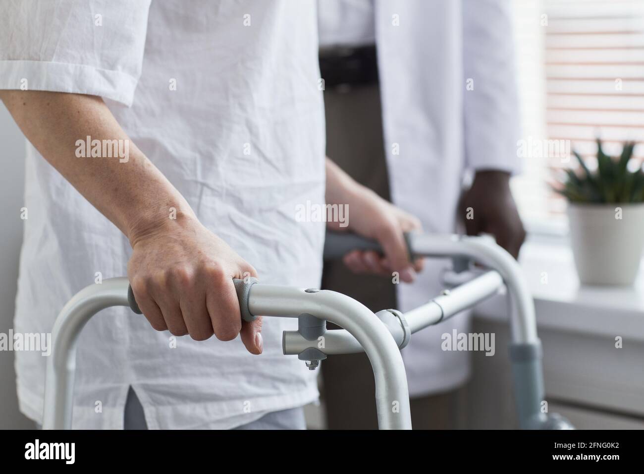 Close-up of senior patient walking with walker along the hospital ward ...
