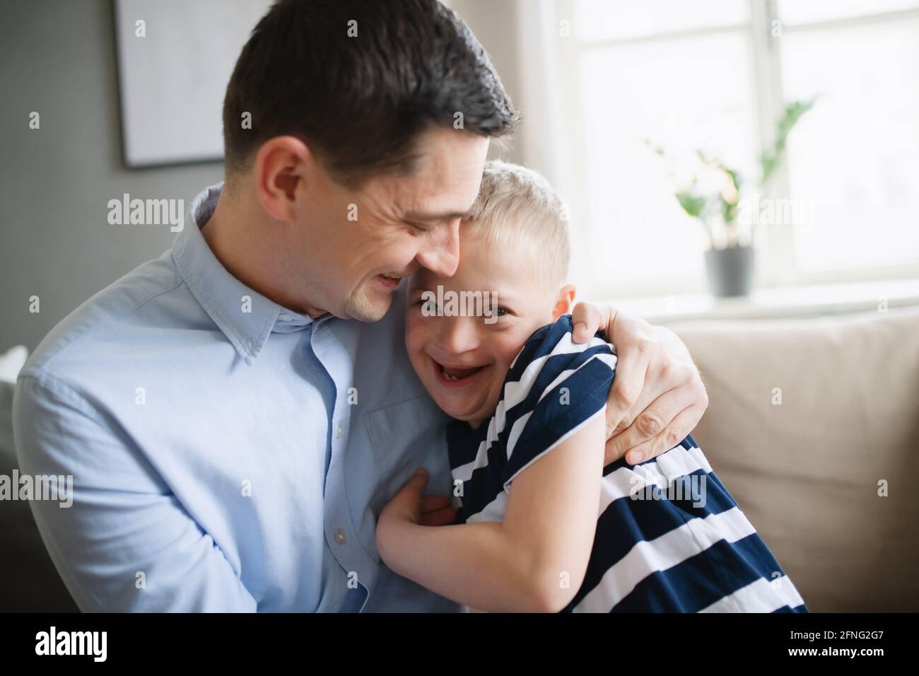 Father with happy down syndrome son indoors at home, hugging and ...
