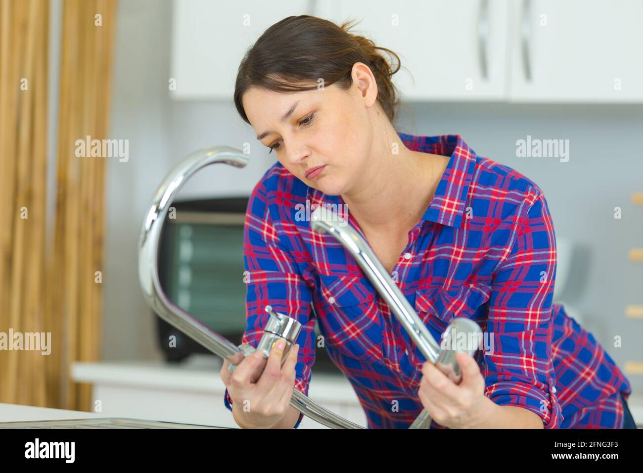 woman is trying to repair a water tap Stock Photo - Alamy