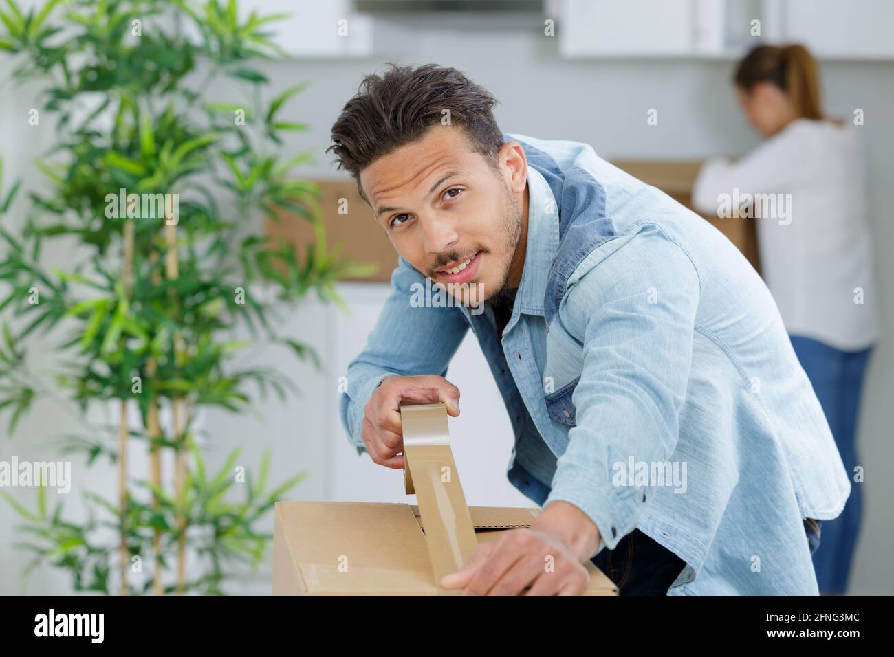 man taping boxes for moving in new apartment Stock Photo - Alamy