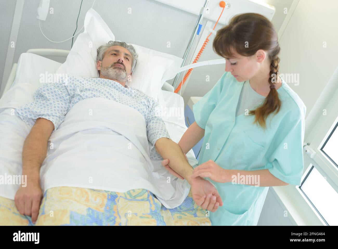 nurse taking patients pulse in hospital bed Stock Photo - Alamy