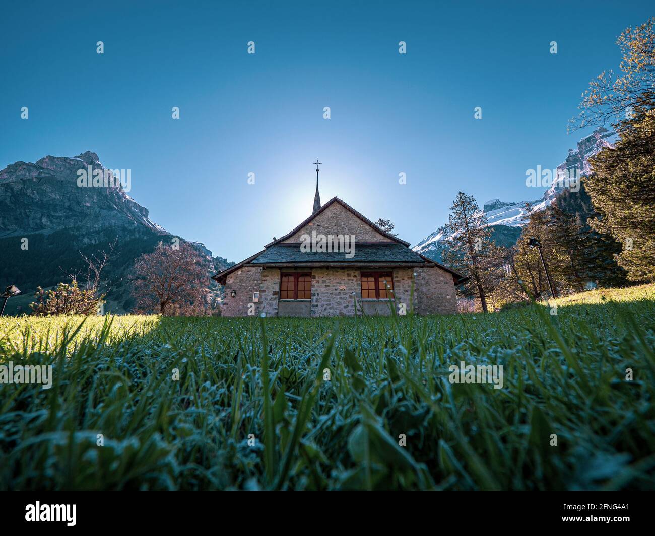 Beautiful old rustic alpine church and snow capped alpine mountains ...