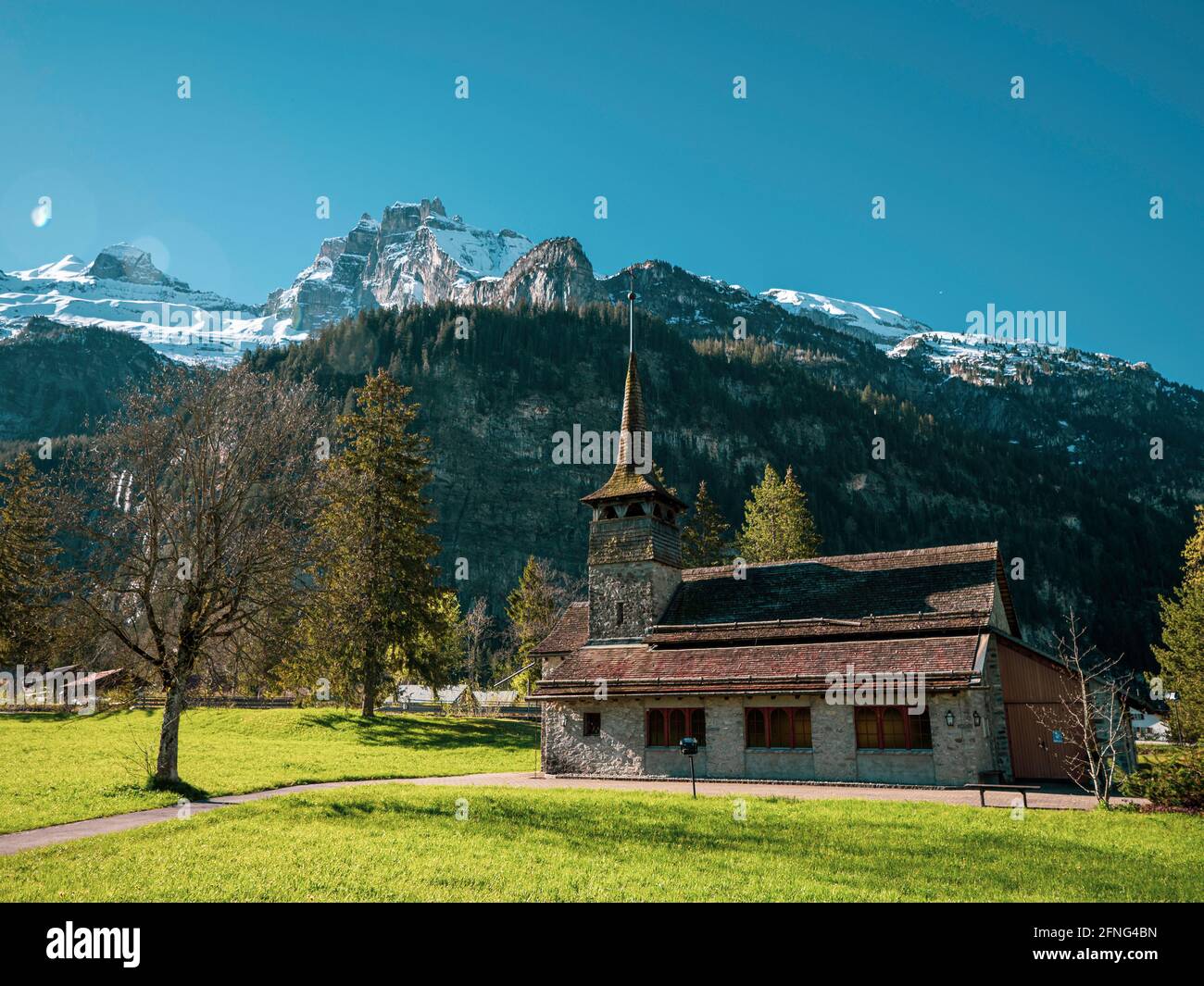 Beautiful old rustic alpine church and snow capped alpine mountains ...