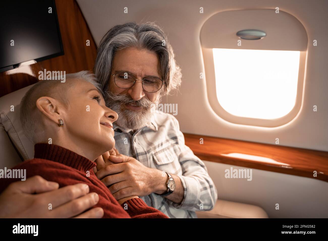 Mature man hugging smiling wife in private jet Stock Photo - Alamy