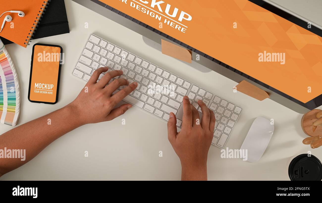 Overhead shot of man typing on keyboard in workspace with mock up ...