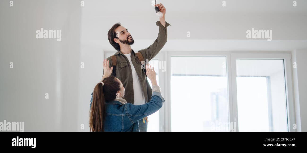 Young couple changing light bulb in new flat, moving, new home and ...
