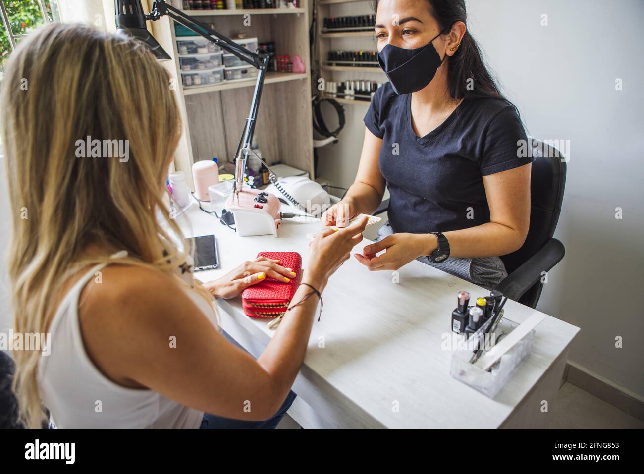 Side view of unrecognizable female customer paying to ethnic master ...