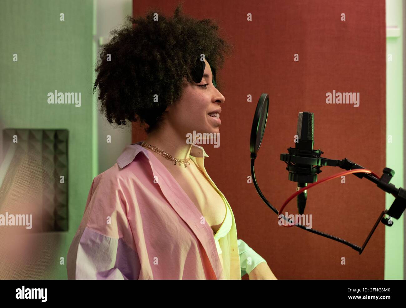 Black female singer performing song against microphone with pop filter ...