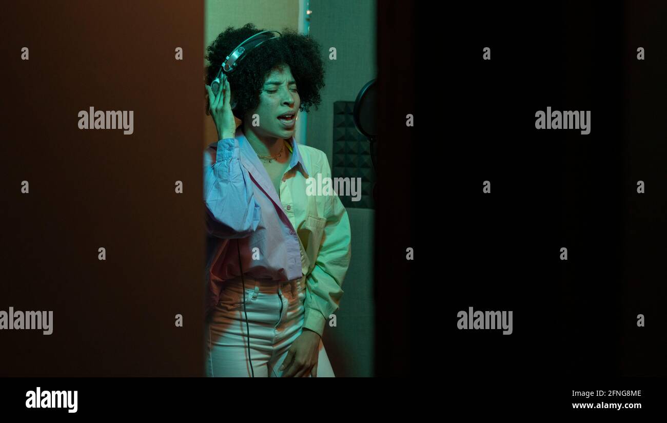 Black female singer performing song against microphone with pop filter ...