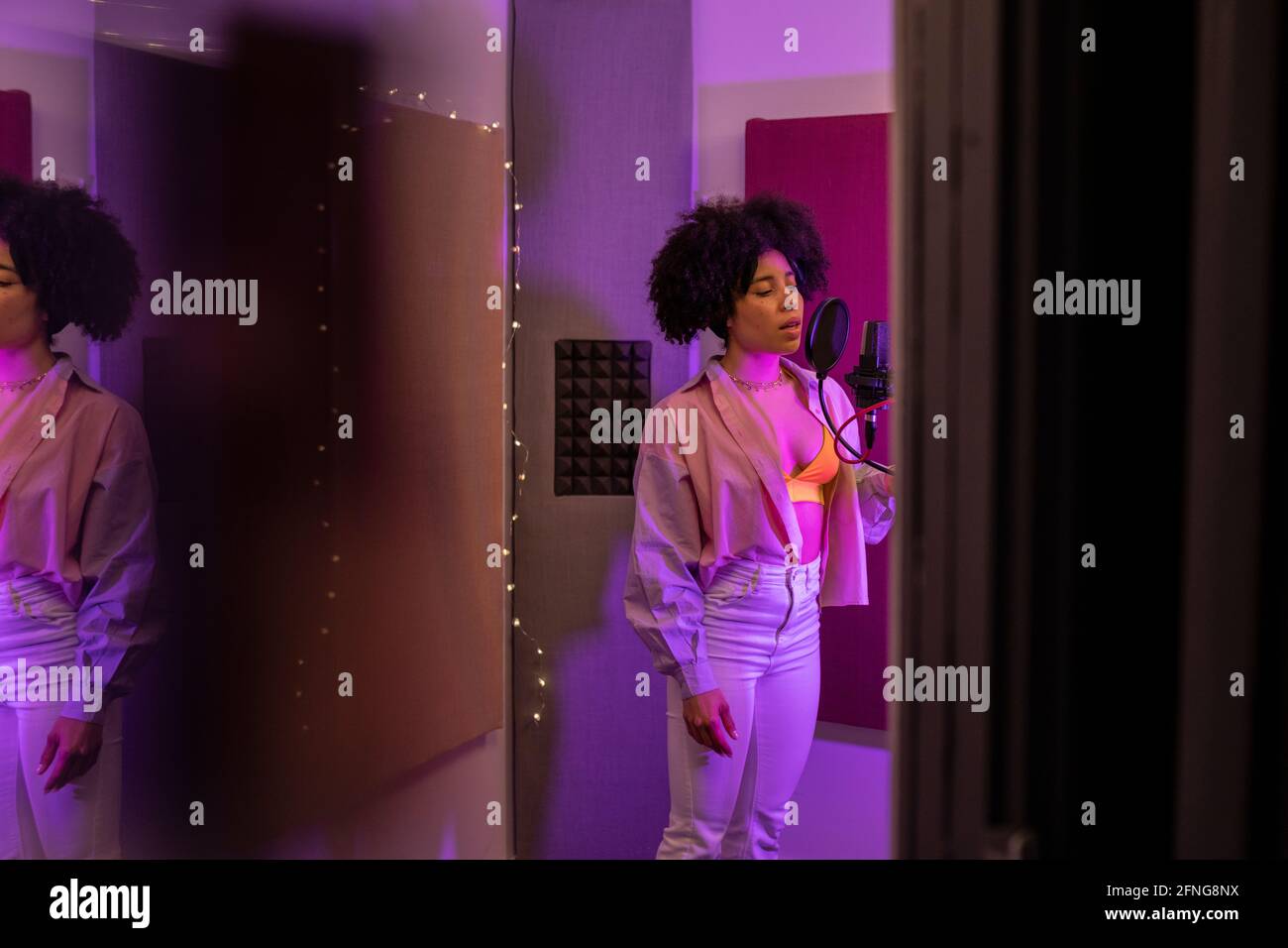 Black female singer performing song against microphone with pop filter ...