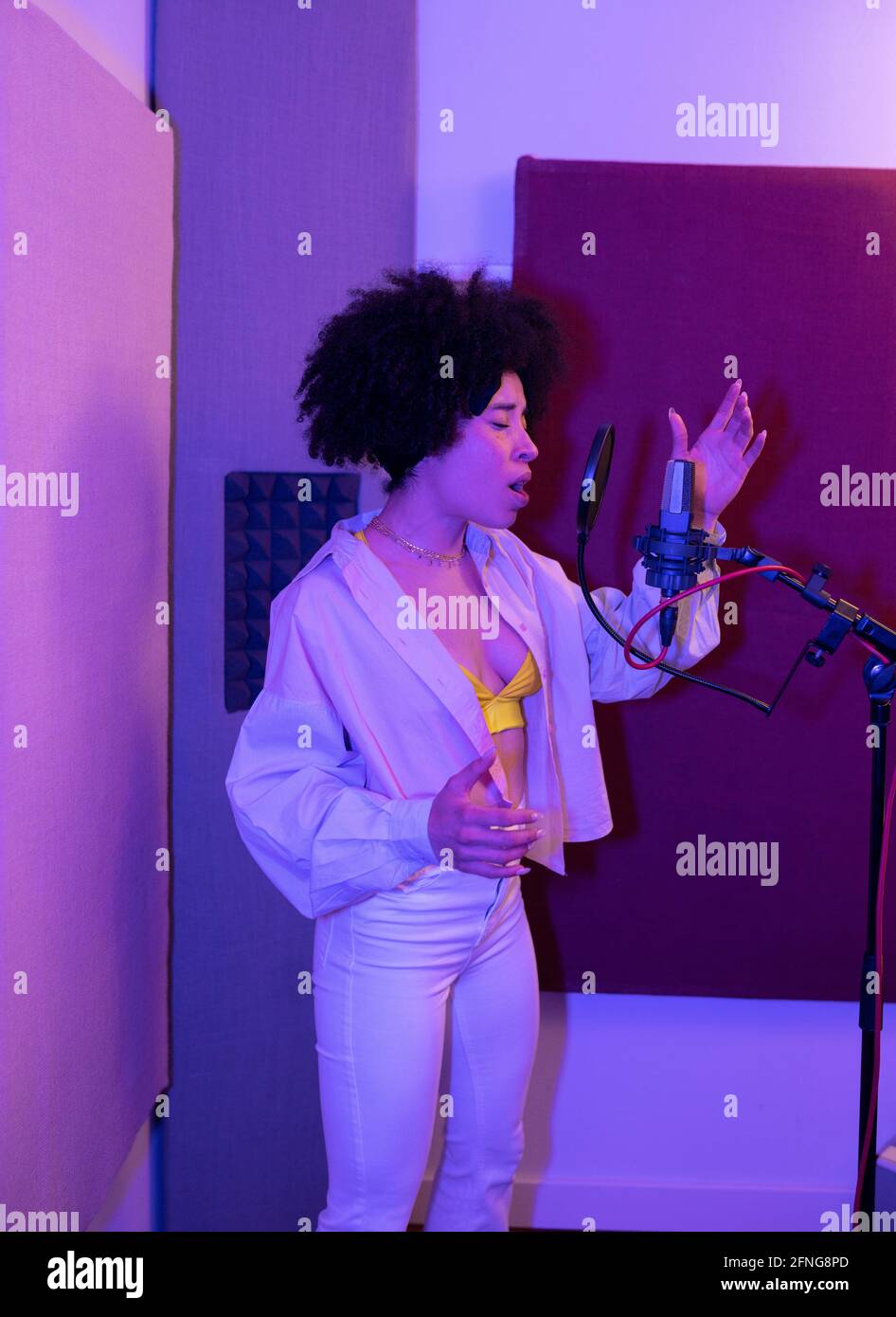 Black female singer performing song against microphone with pop filter ...