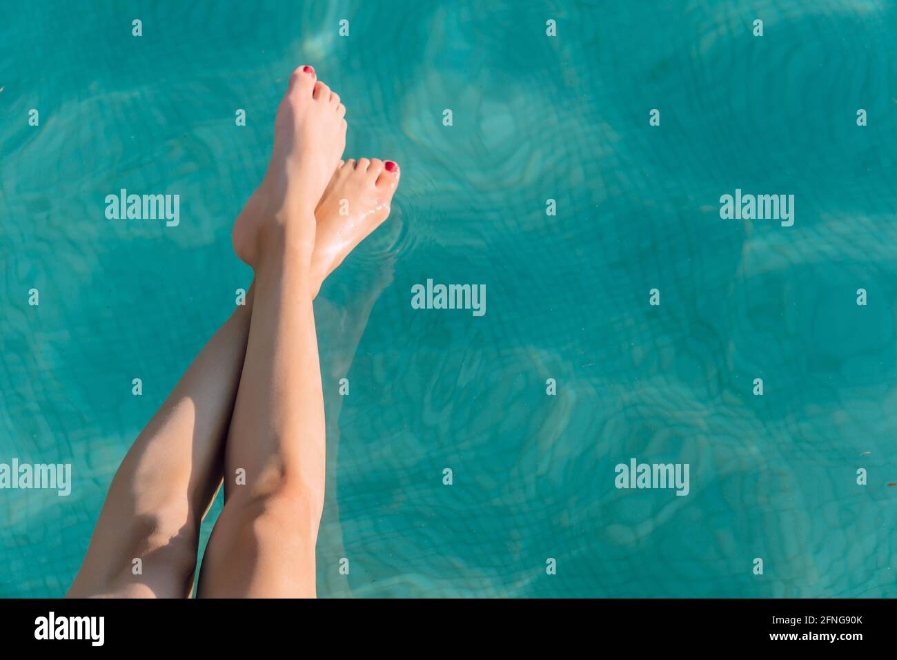 Crop anonymous barefoot female travelers touching shiny rippled water ...