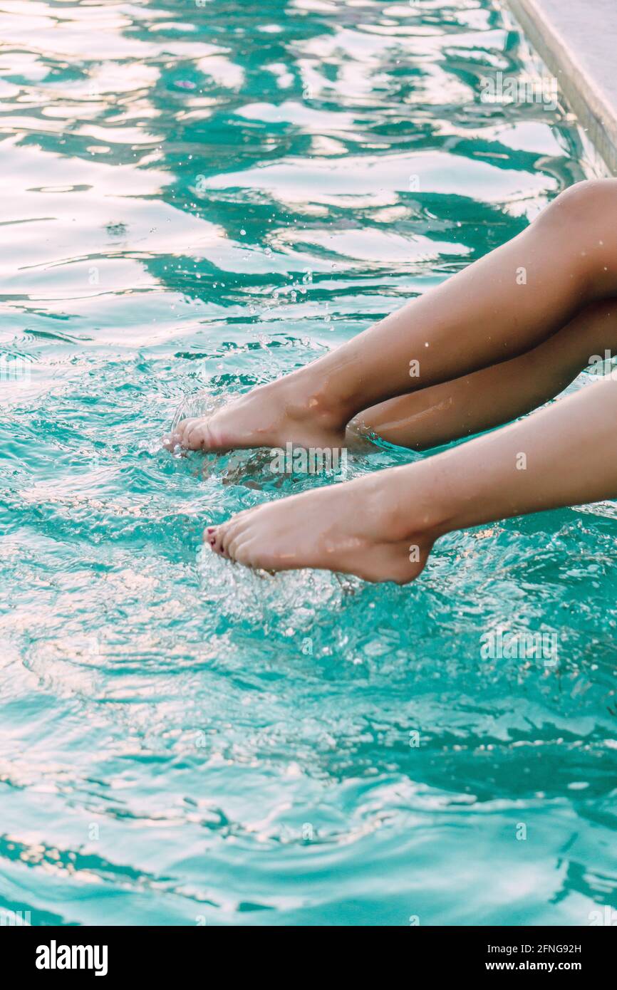 Crop anonymous barefoot female travelers touching shiny rippled water ...