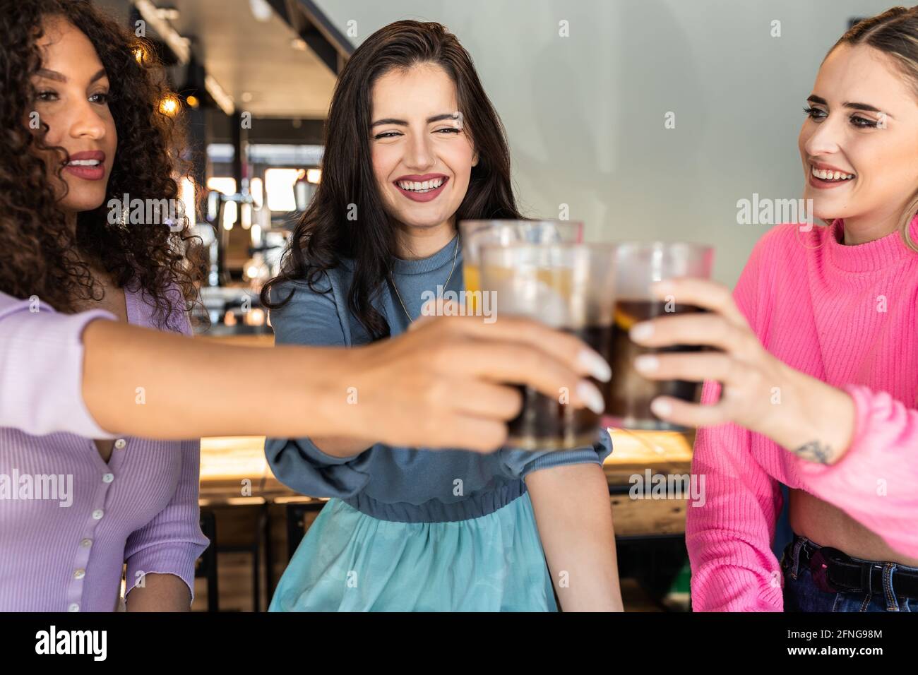 Joyful young multiethnic female best friends in stylish colorful ...