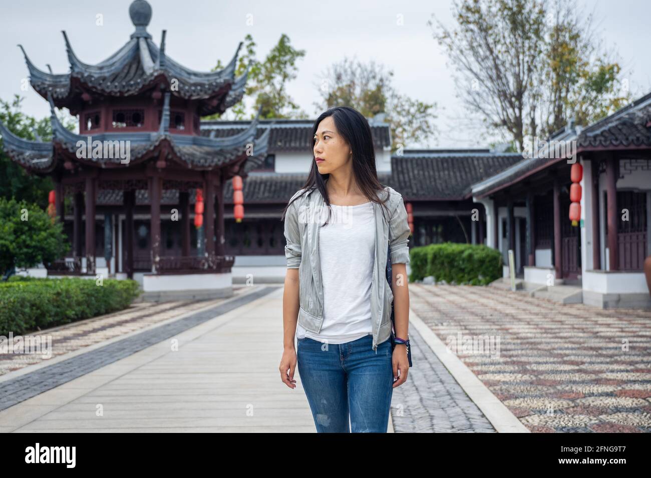 Beautiful Asian Woman walking in a Chinese garden with traditional ...