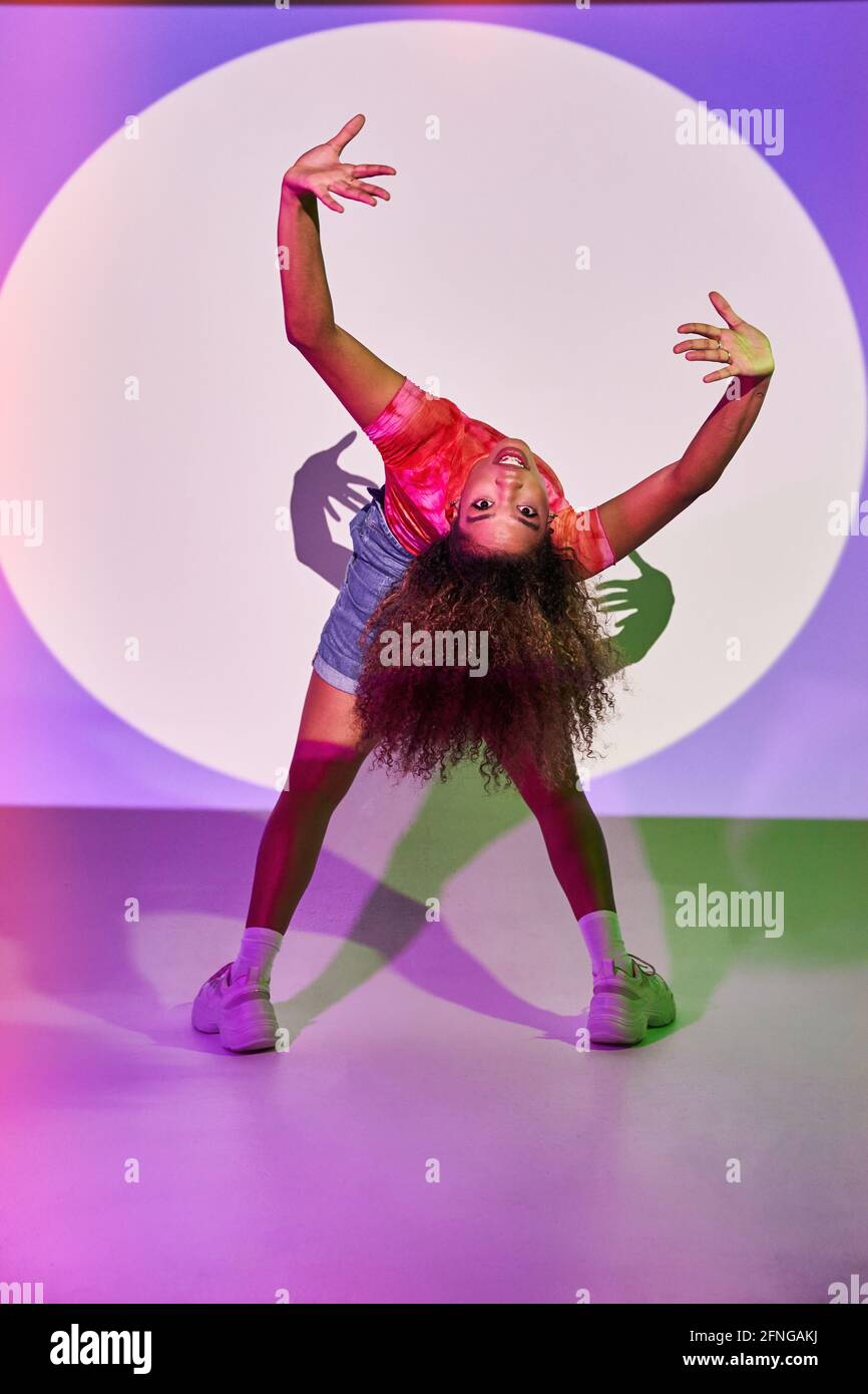Back view flexible African American female dancer in shorts bending ...