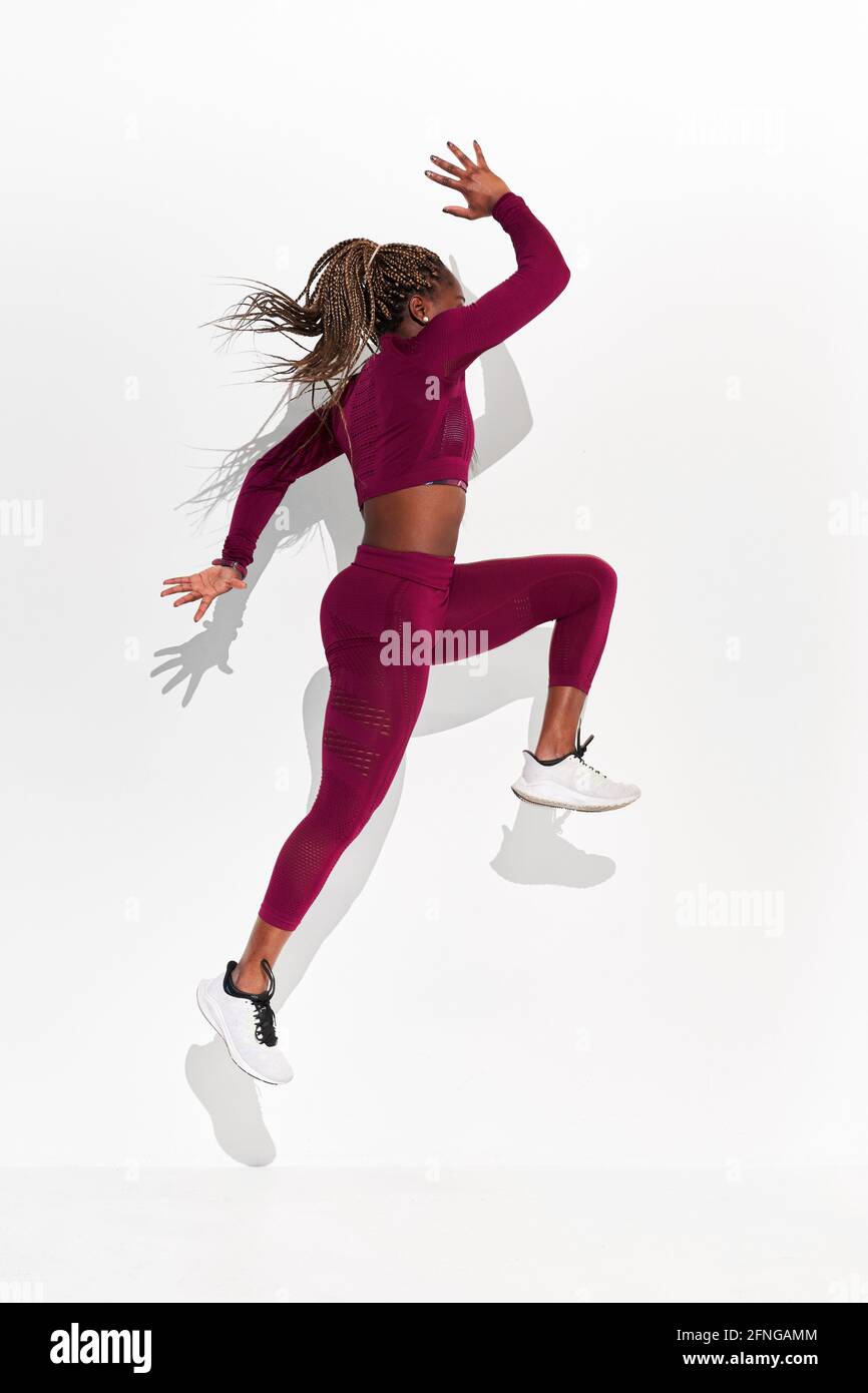 Side view of determined African American sportsWoman jumping with ...
