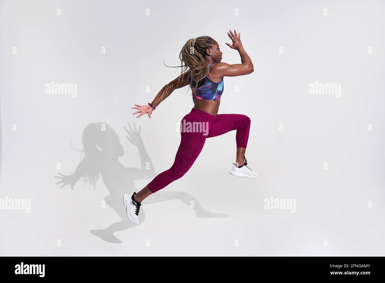Side view of determined African American sportsWoman jumping with ...