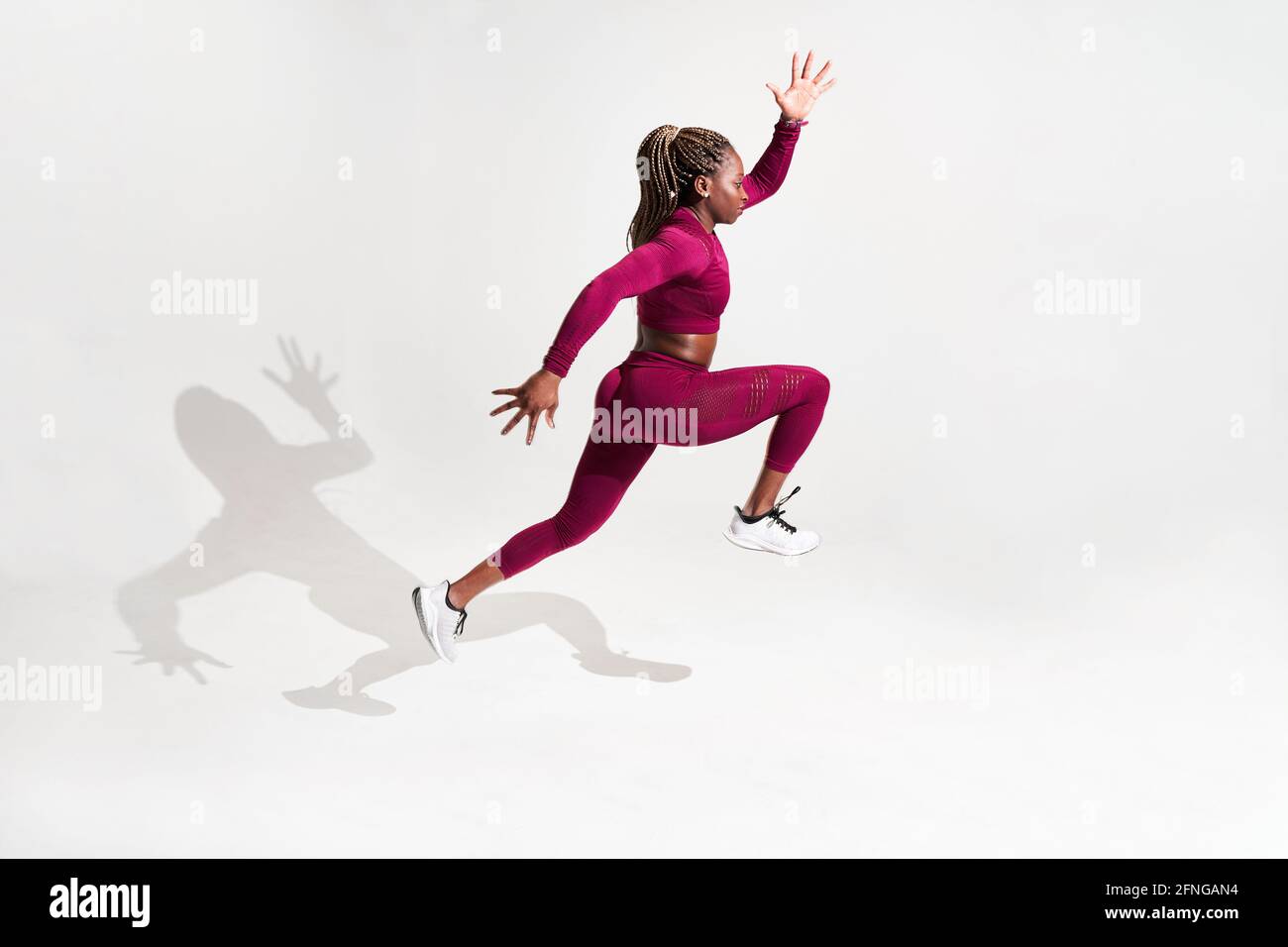 Side view of determined African American sportsWoman jumping with ...