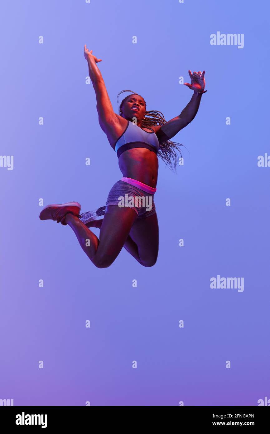 Side view of determined African American sportsWoman jumping with ...