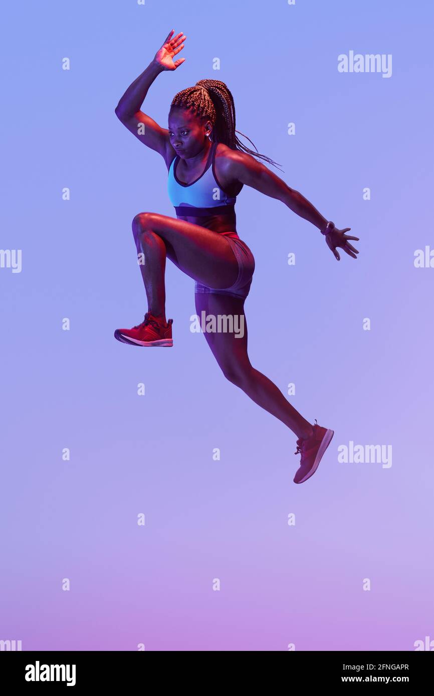Side view of determined African American sportsWoman jumping with ...