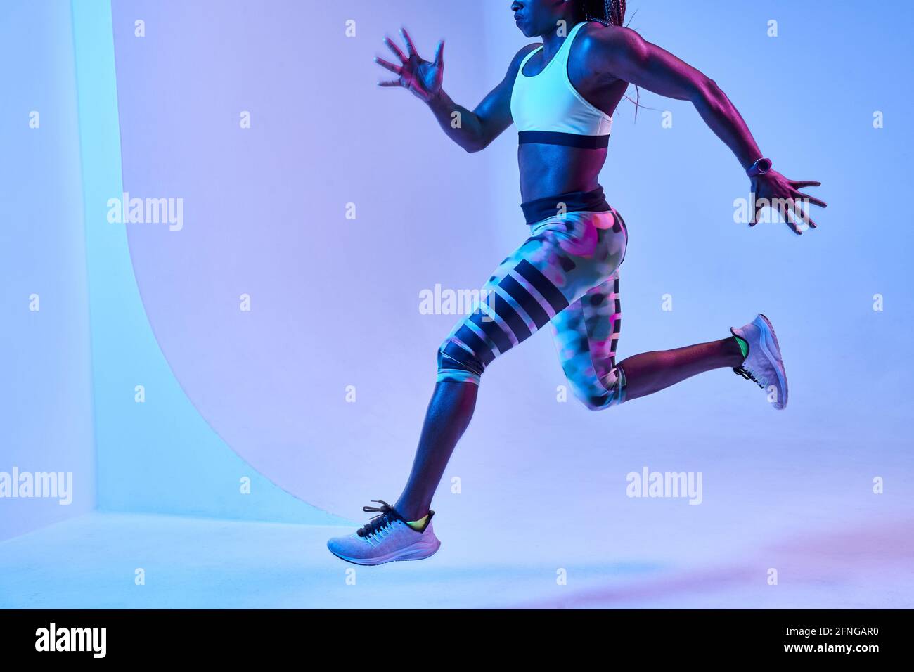 Side view of determined African American female athlete jumping while ...