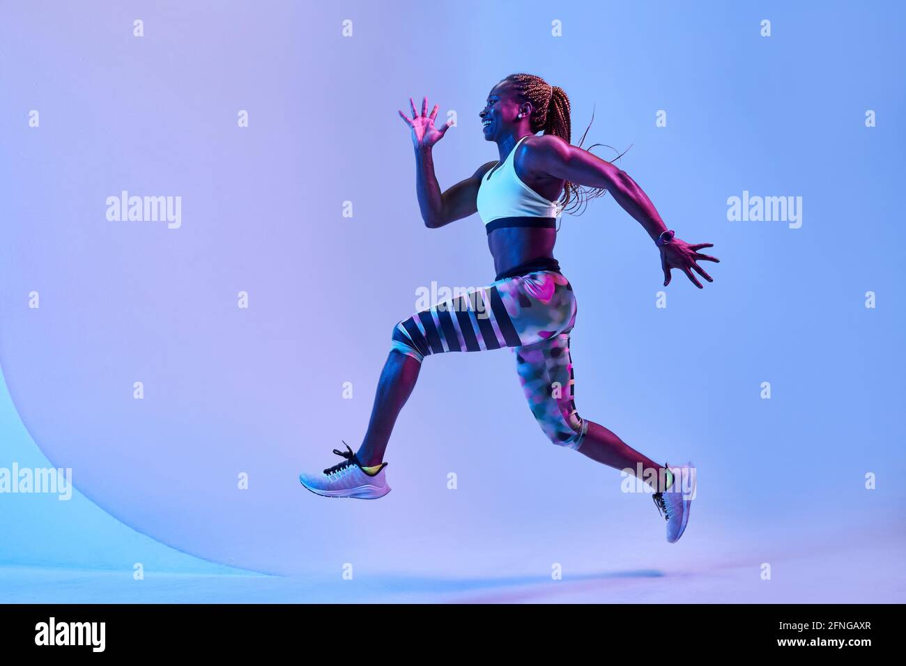 Side view of determined African American female athlete jumping while ...