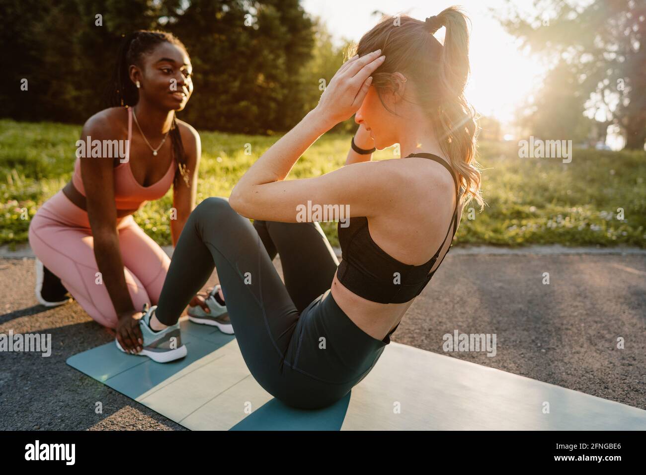 Side view of slim female athlete doing abdominal crunches with help of ...