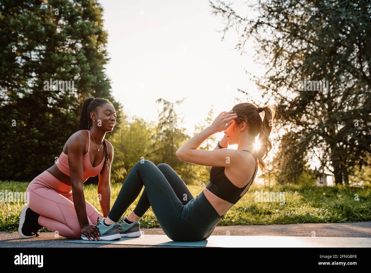 Side view of slim female athlete doing abdominal crunches with help of ...