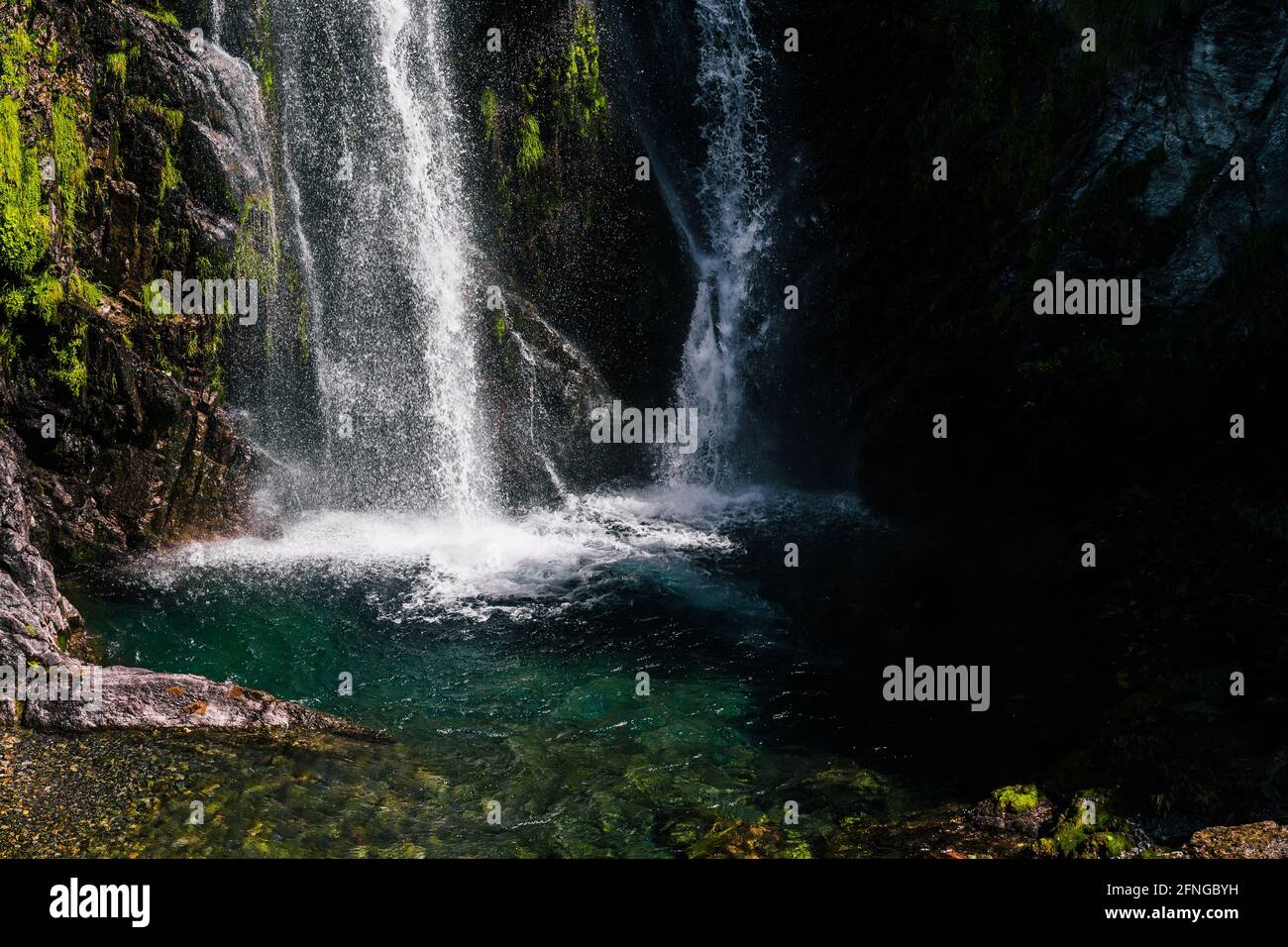 Scenic view of waterfall with foamy water fluids in pond between mounts ...