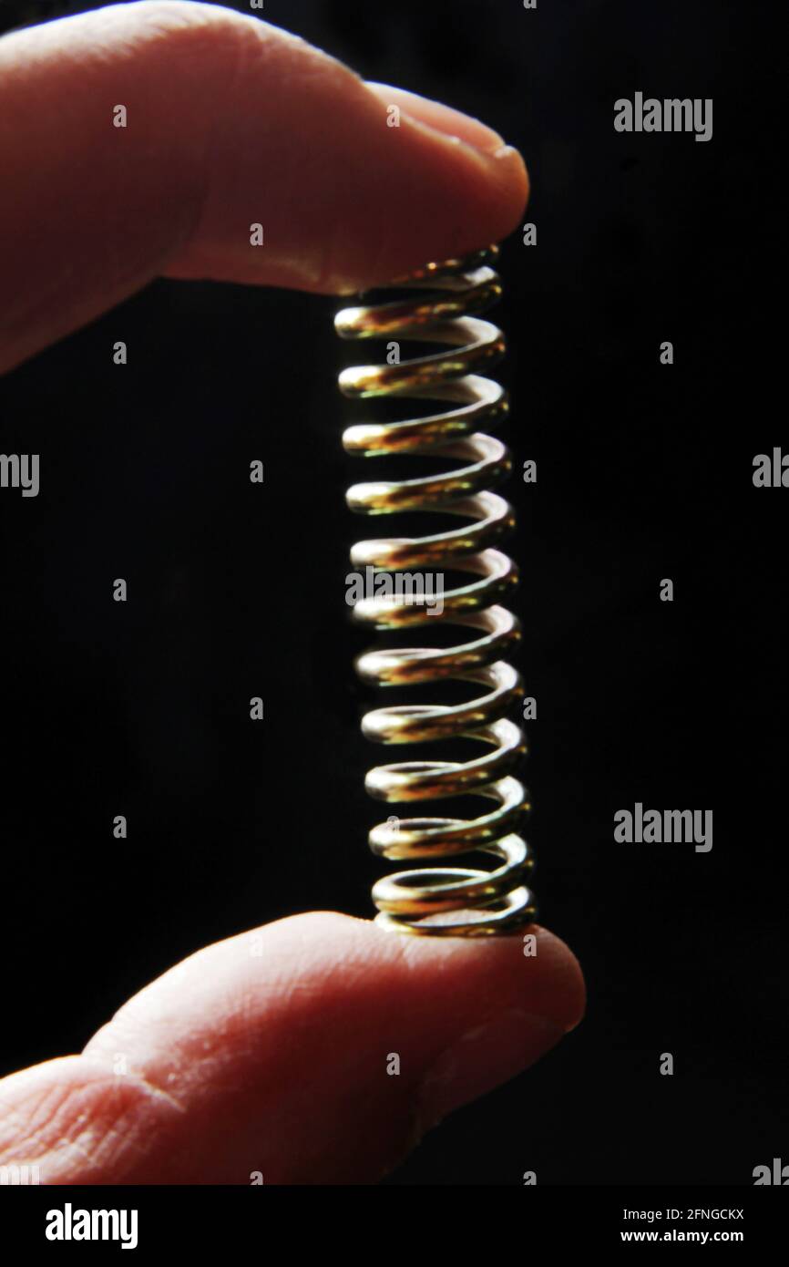 Hand squeezes a metal spring hi-res stock photography and images - Alamy
